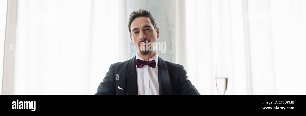 wealthy and confident gentleman in tuxedo with bow tie looking at ...