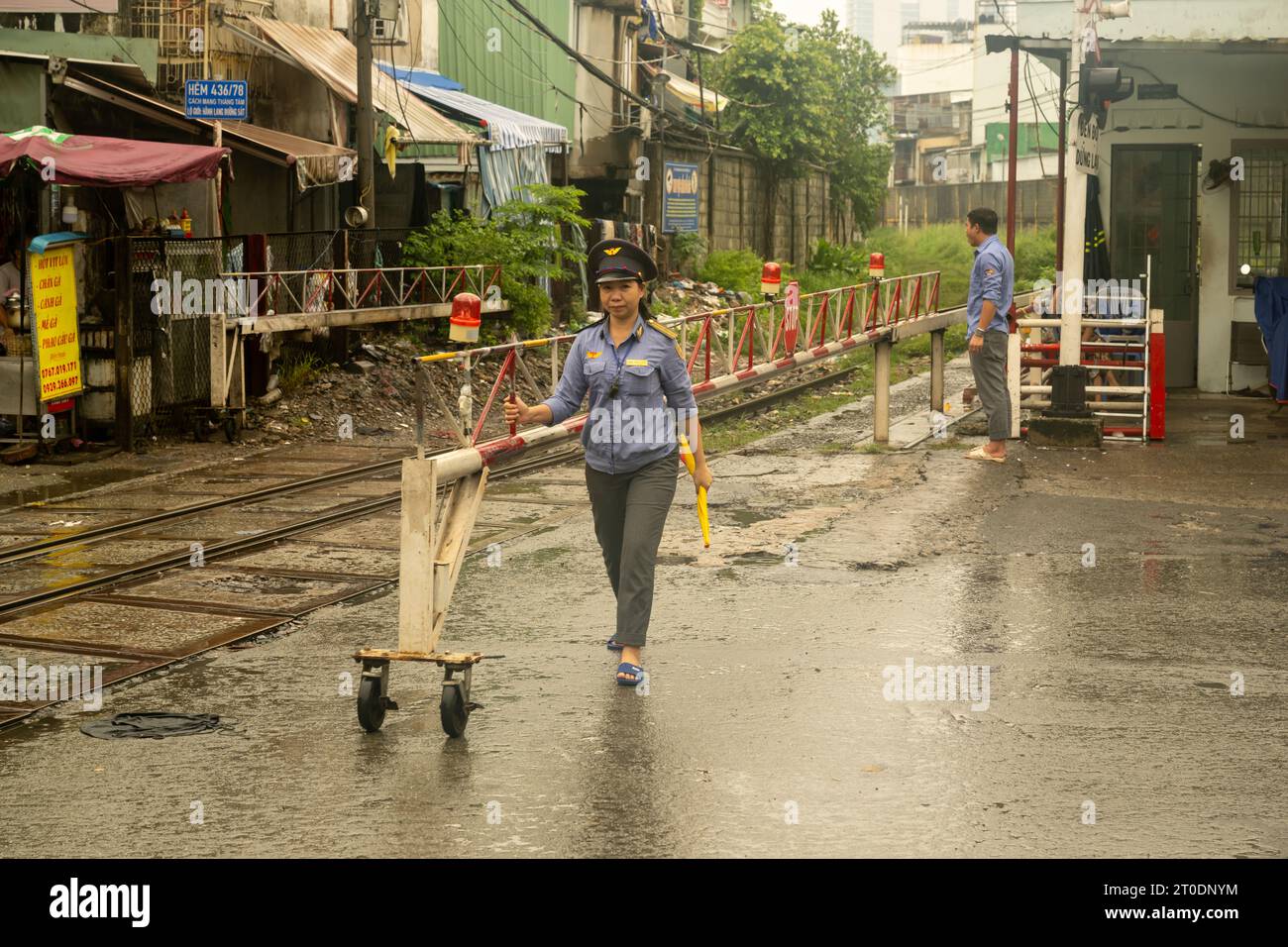 Closing the gates for a passing train at the famous Saigon railway ...