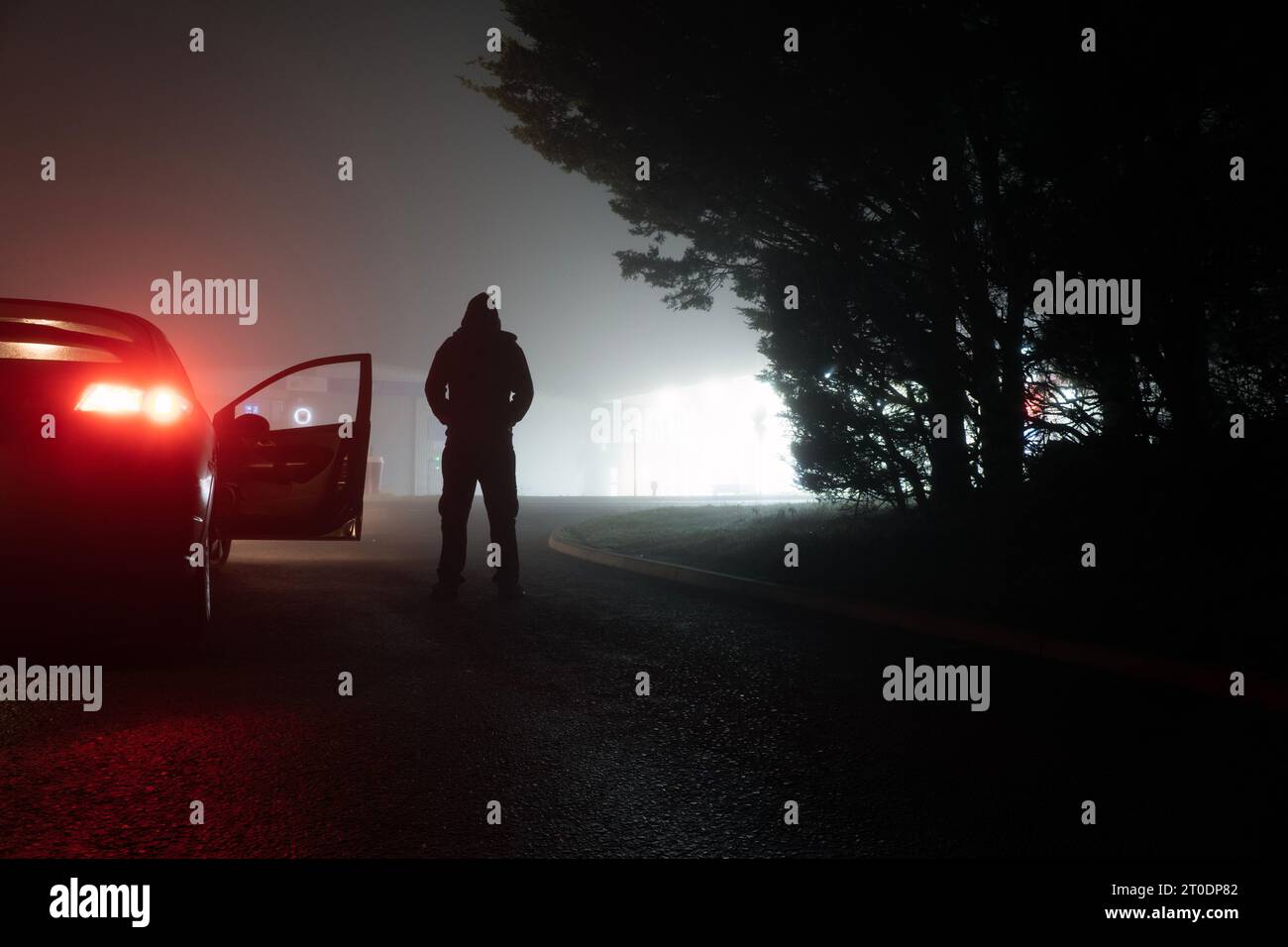 A mysterious scary hooded figure. Standing next to a parked car on a ...