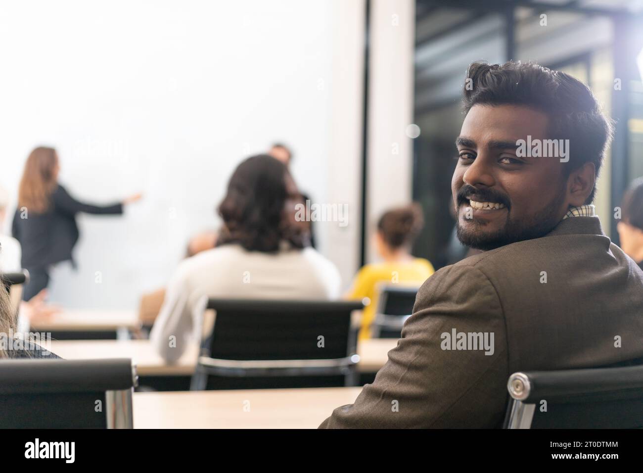 An Indian businessman smiling during a group of diverse employees ...