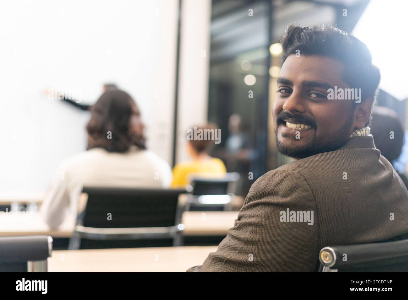 An Indian businessman smiling during a group of diverse employees business people team ...