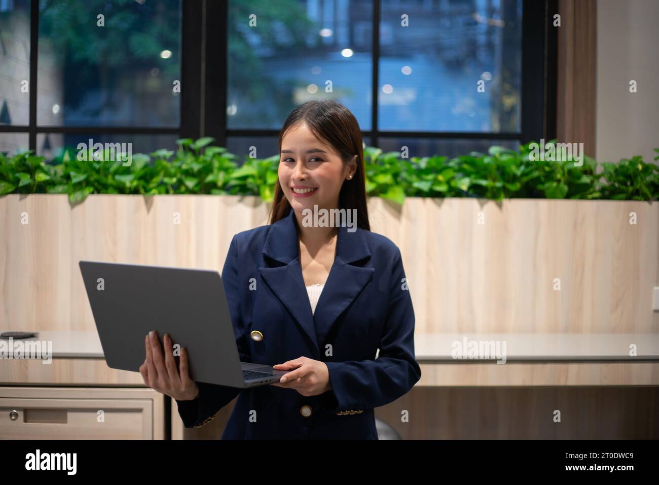 Happy young Asian saleswoman holding laptop. Smiling business woman ...