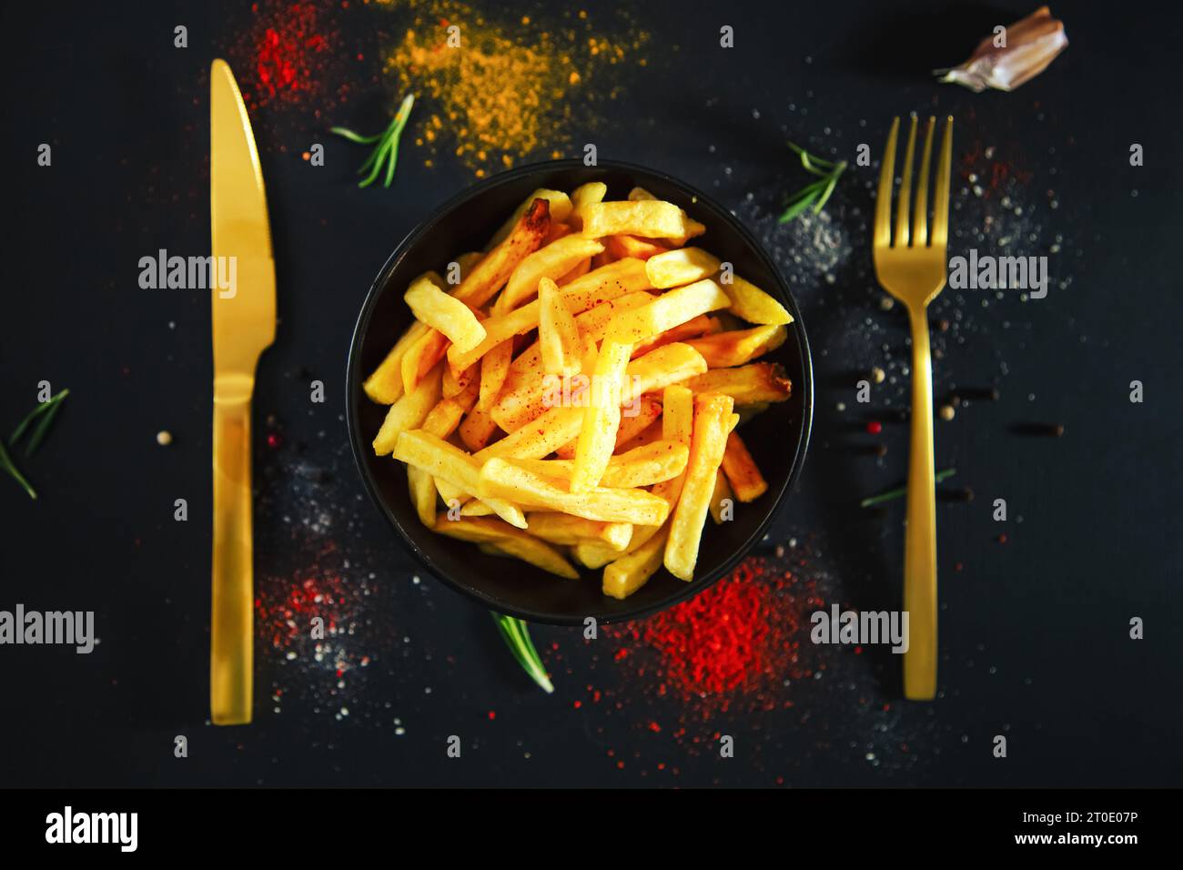 French fries with spices on a black background. Food background, flat ...