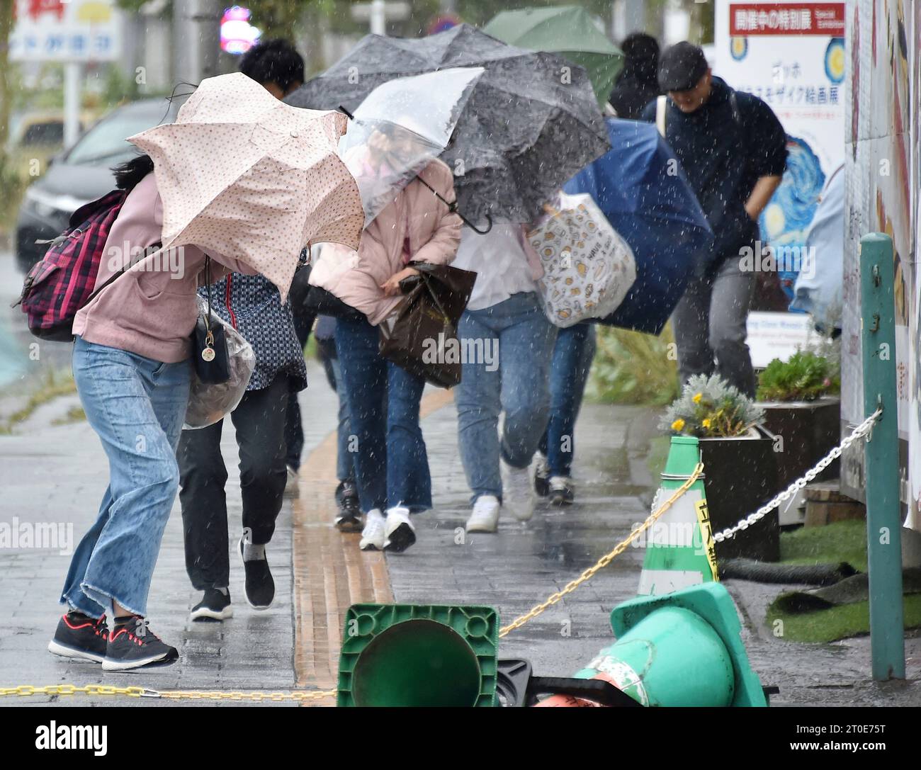 People walk in a rainstorm to avoid having their umbrellas blown away ...