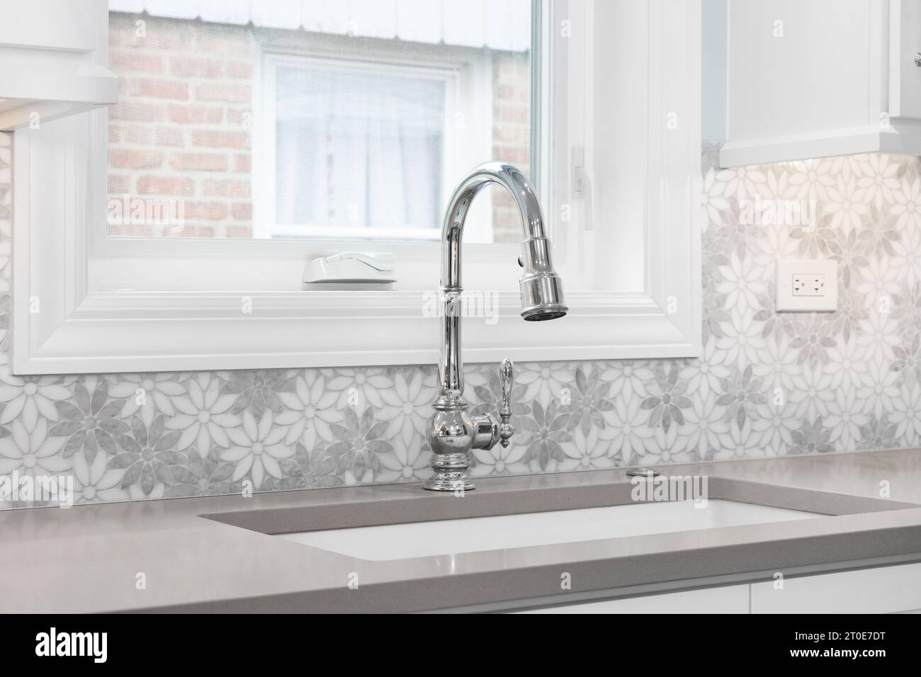 A kitchen faucet detail with a marble daisy flower tiled backsplash ...