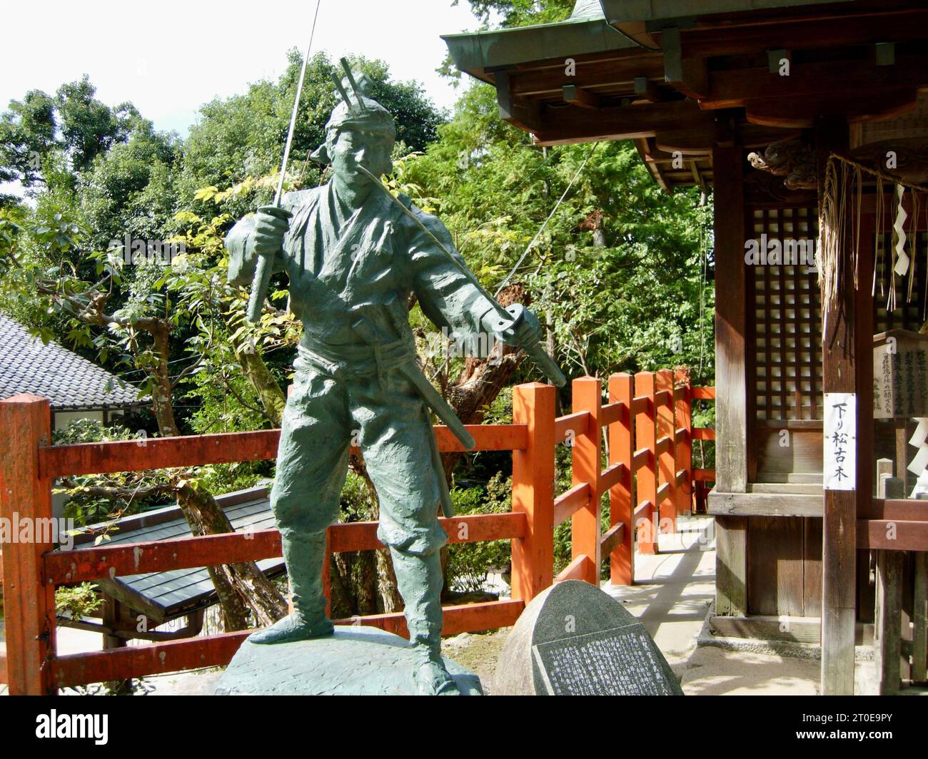 A bronze statue of a man is standing atop a large stone block in front ...