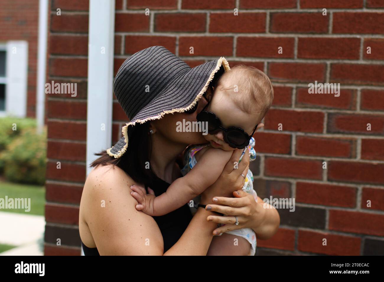 A young female parent cradling a small infant in her arms while wearing ...
