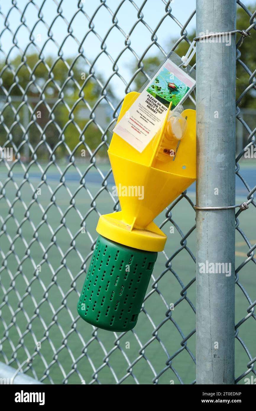 Japanese Beetle trap attached to a fence pool with informational label ...