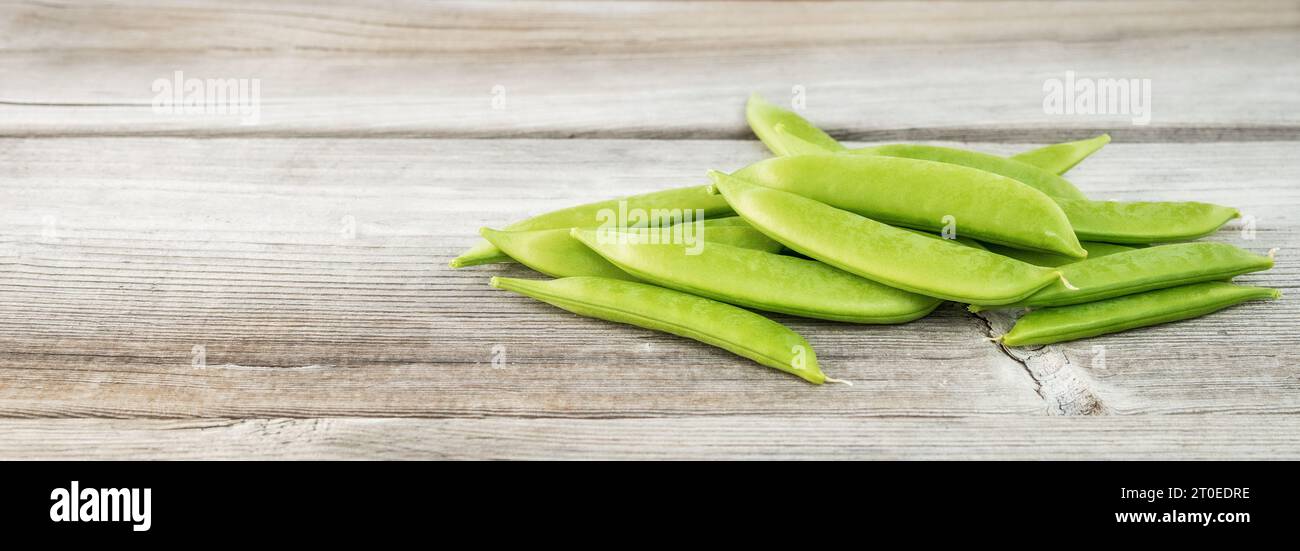 Pile of snap peas on wood table. Group of fresh green pea pod shells ...