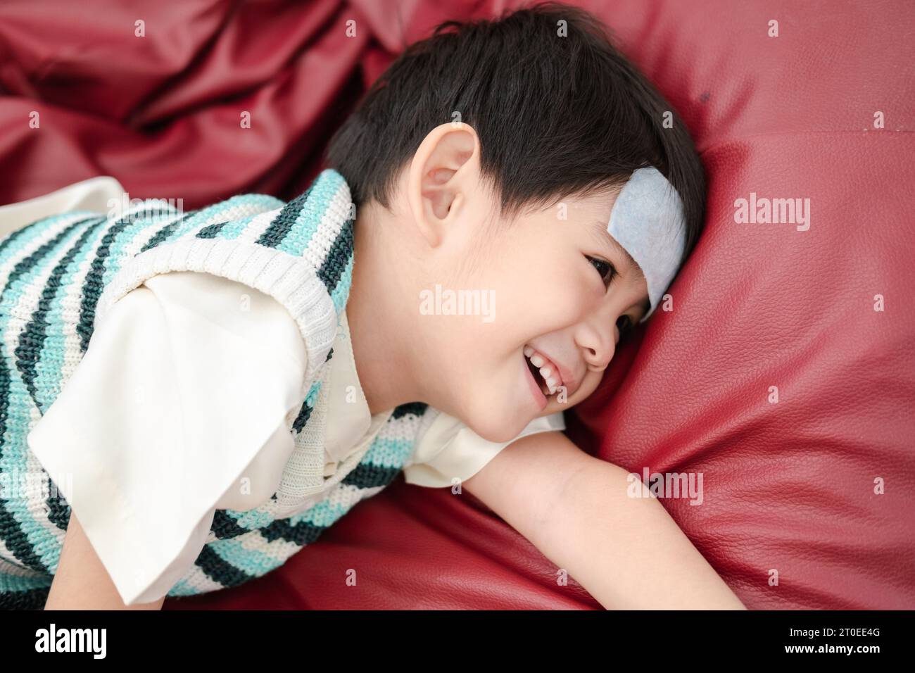 Asian boy Lying sick with a fever reducing patch on her forehead but ...