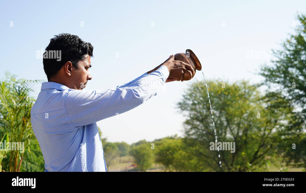 Hindu man offering prayer. Worshipping in Hinduism. A round metal pot ...