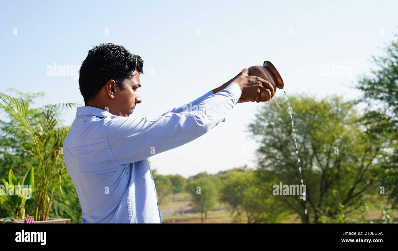 Hindu devotee offering water or Ardhya to the sun God at home on ...