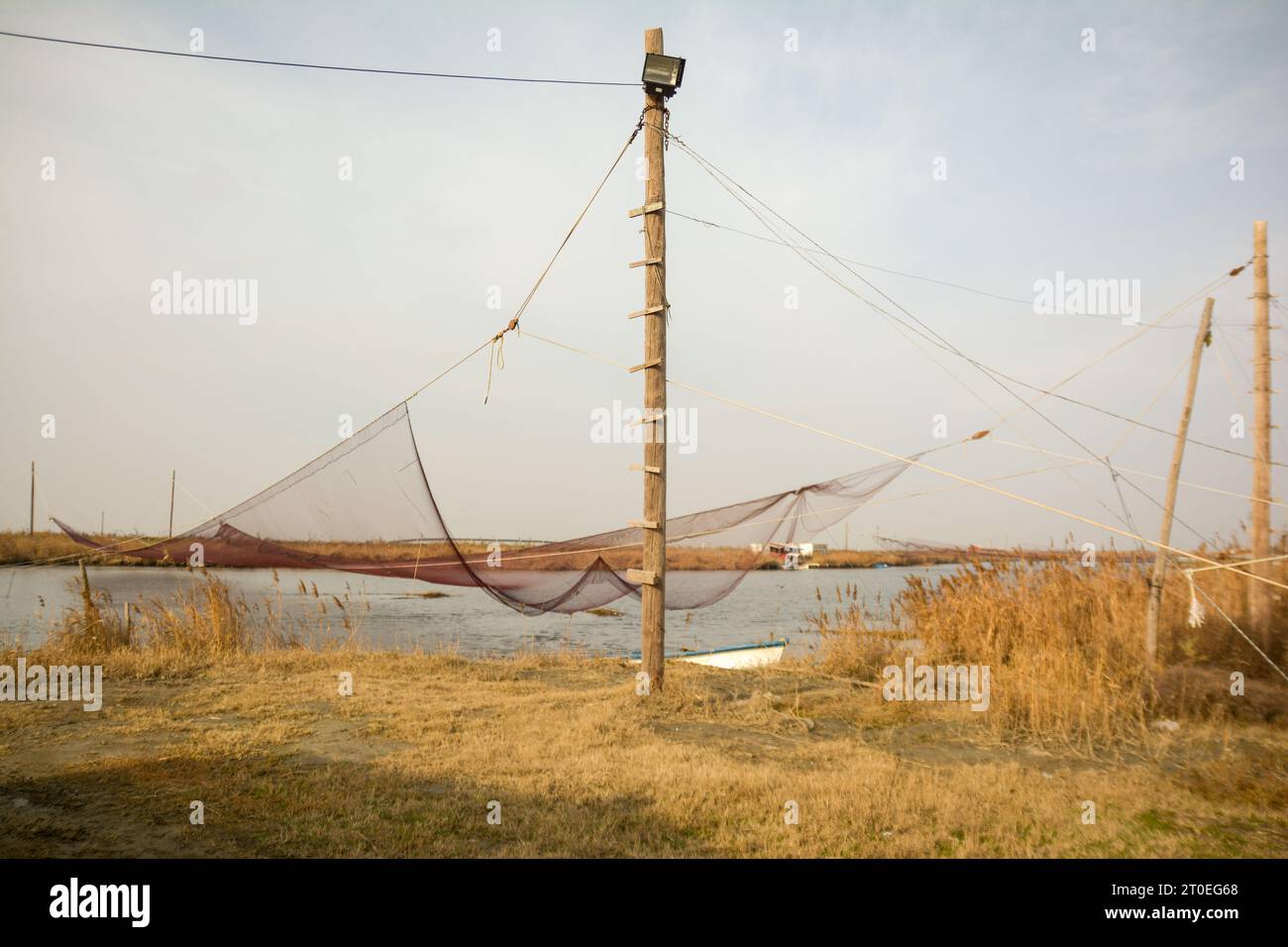 Two small boats tied to power lines on the shoreline of a lake or river ...