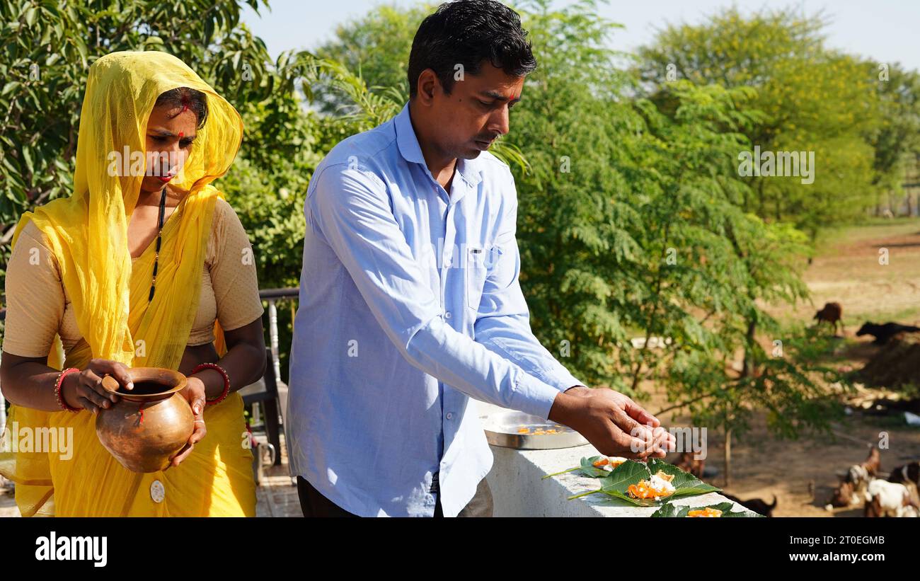 Indian religious family placed food on a leaf for the crow bird to eat ...