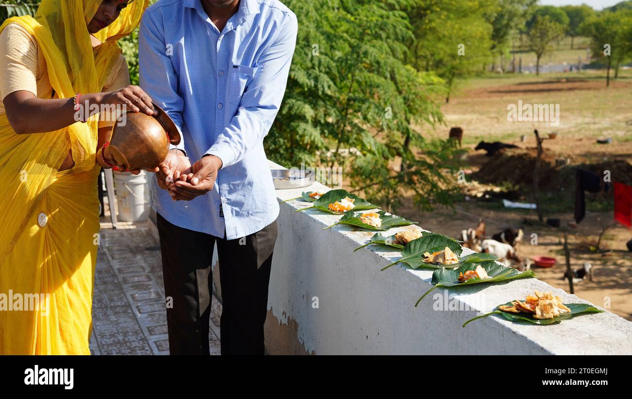 Hindu religious man with his wife offering food placed on a green leaf ...