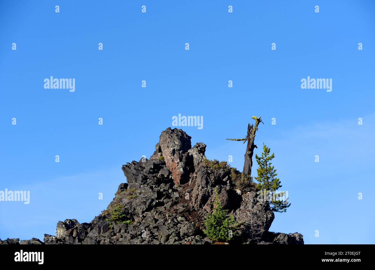 Large mound, of basalt lava rock, projects into a blue morning sky ...