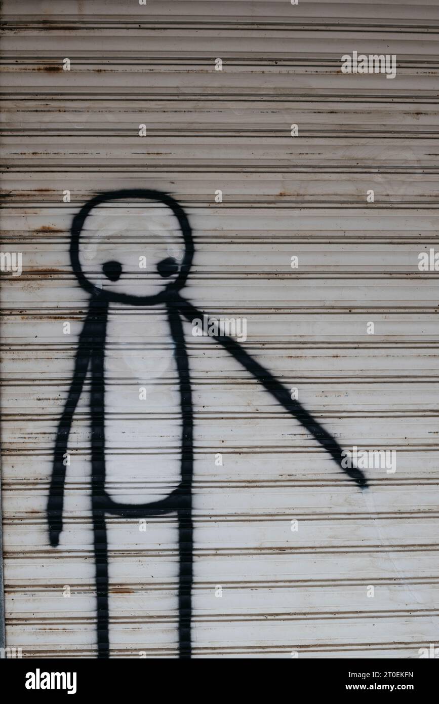 Black graffiti stick figure on a derelict roller shutter in Playa Honda ...