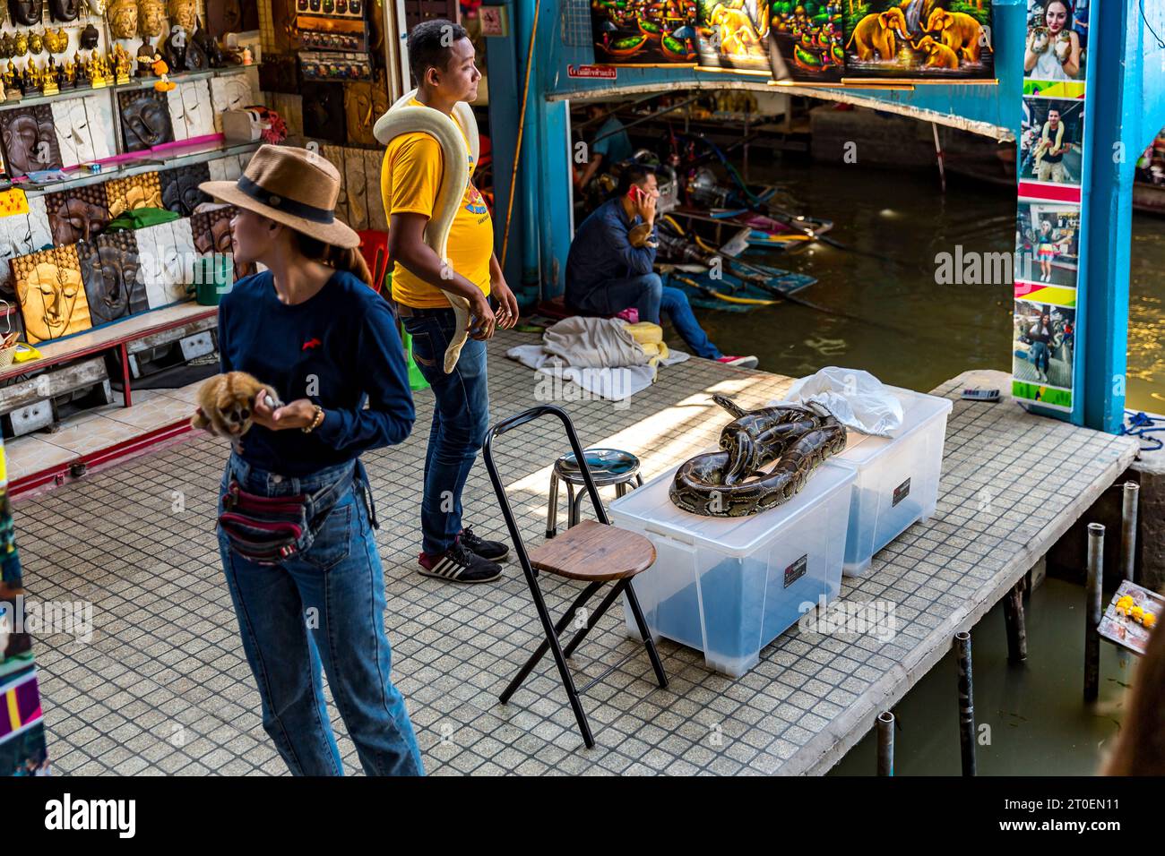 Woman and man offer snakes and small monkey for photograph, floating ...