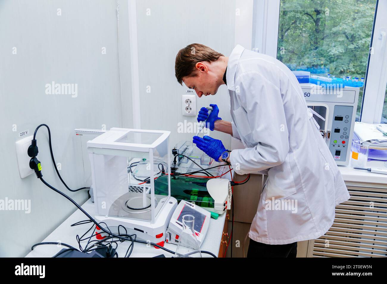 Scientist with gloved hand putting DNA sample into real-time PCR-cycler ...