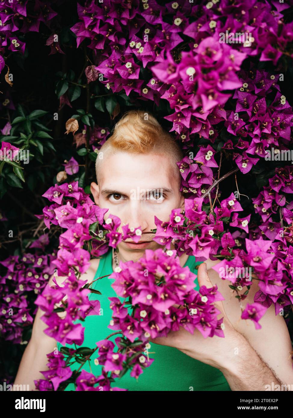 Non binary with green top in front of shrub with flowers hi-res stock ...