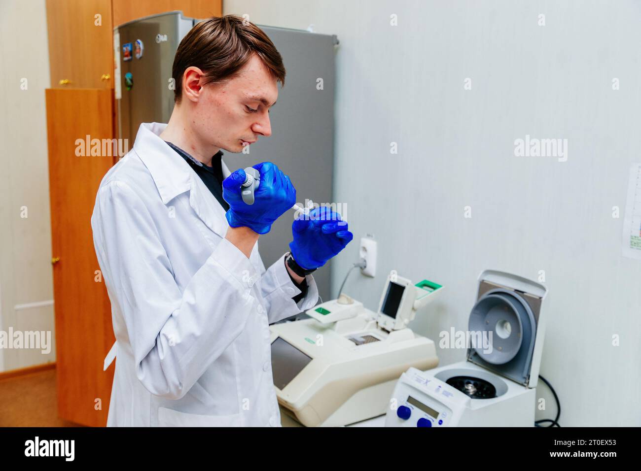 Scientist with gloved hand putting DNA sample into real-time PCR-cycler ...