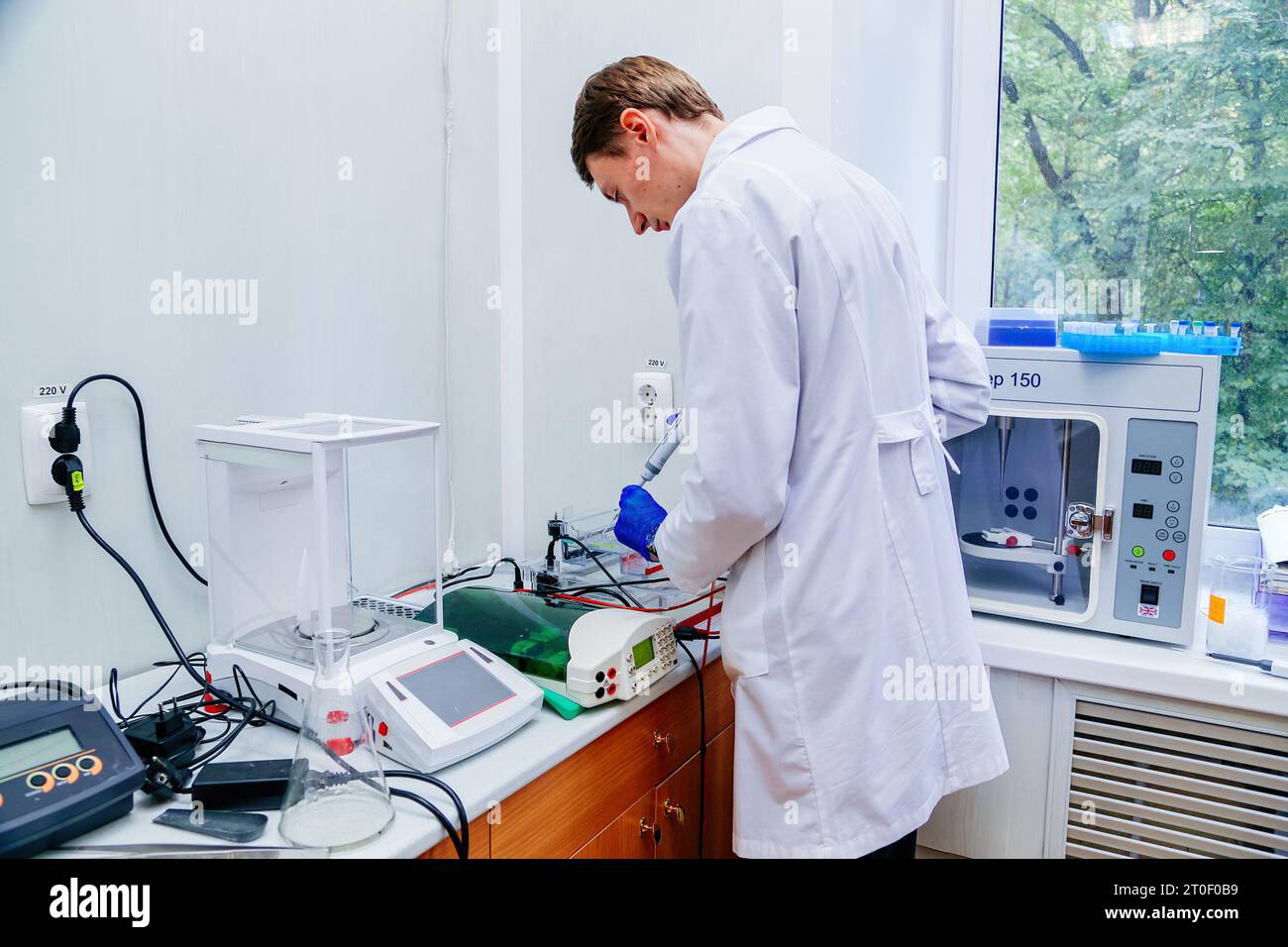 Scientist with gloved hand putting DNA sample into real-time PCR-cycler ...