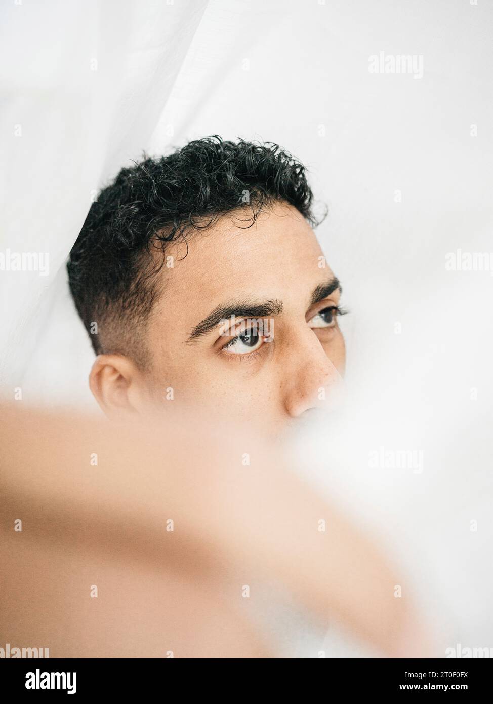 Non-binary man with black t-shirt behind curtain Stock Photo - Alamy