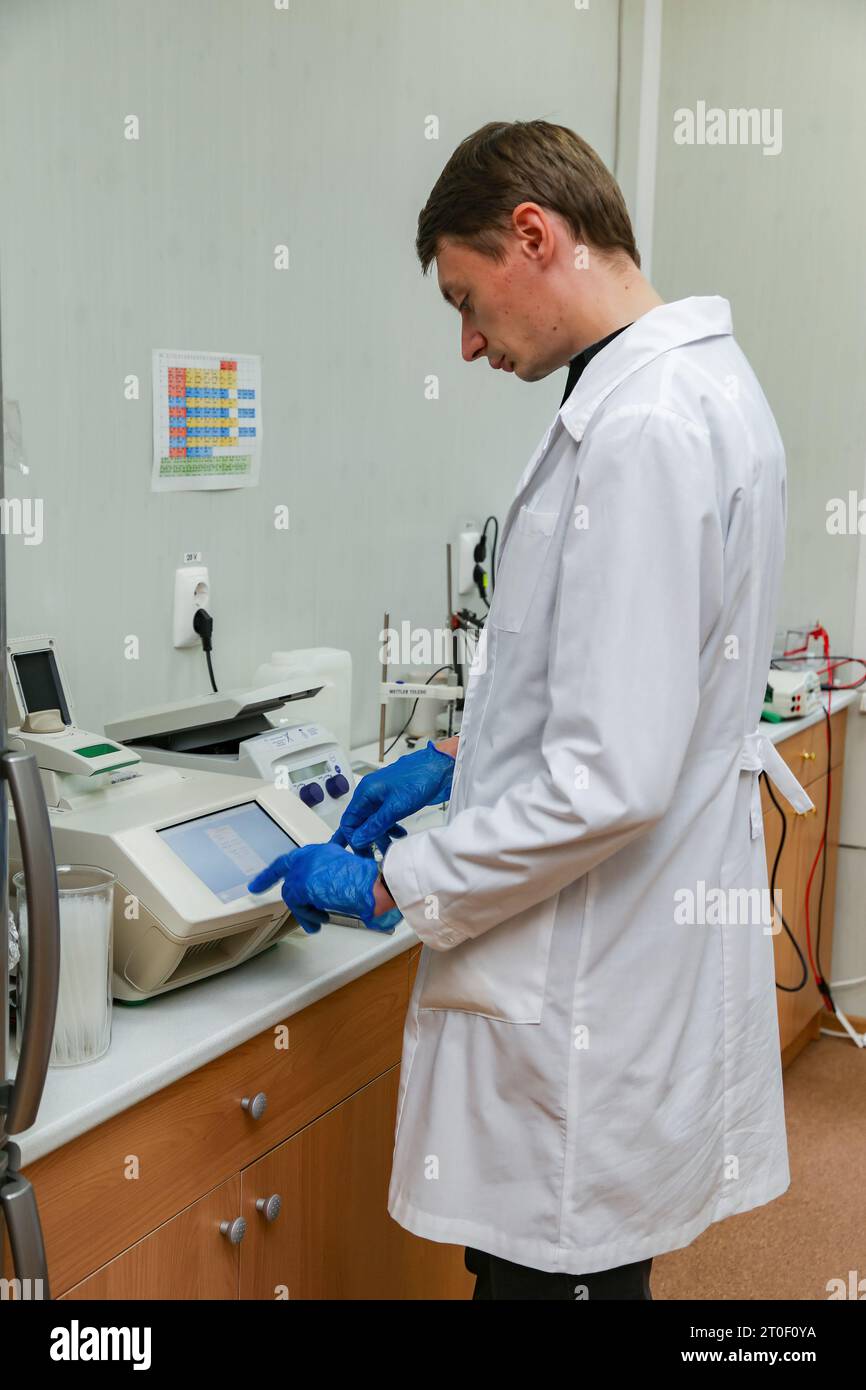 Scientist with gloved hand putting DNA sample into real-time PCR-cycler ...