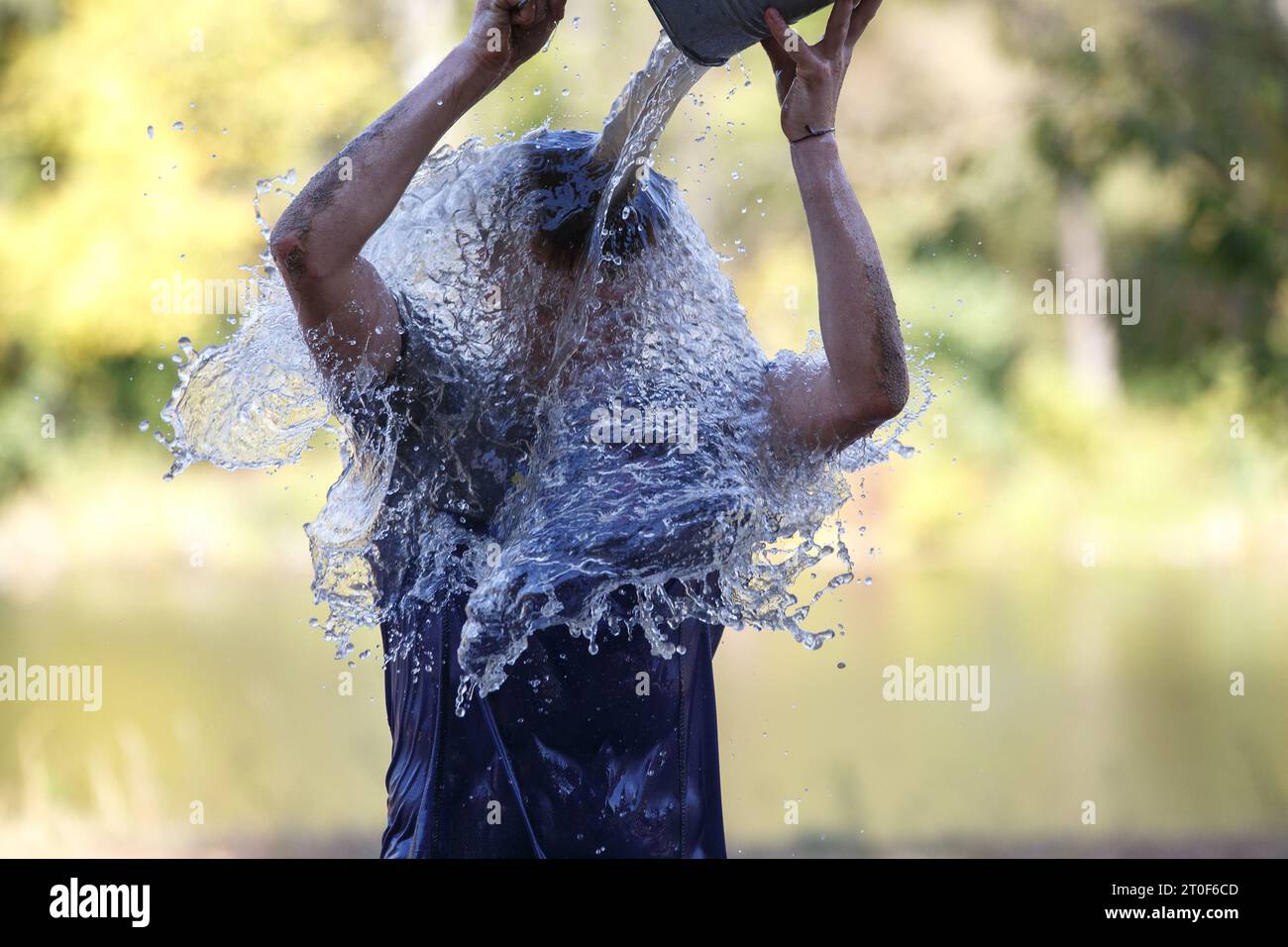 A man pouring bucket of water on his head as an element in obstacle ...