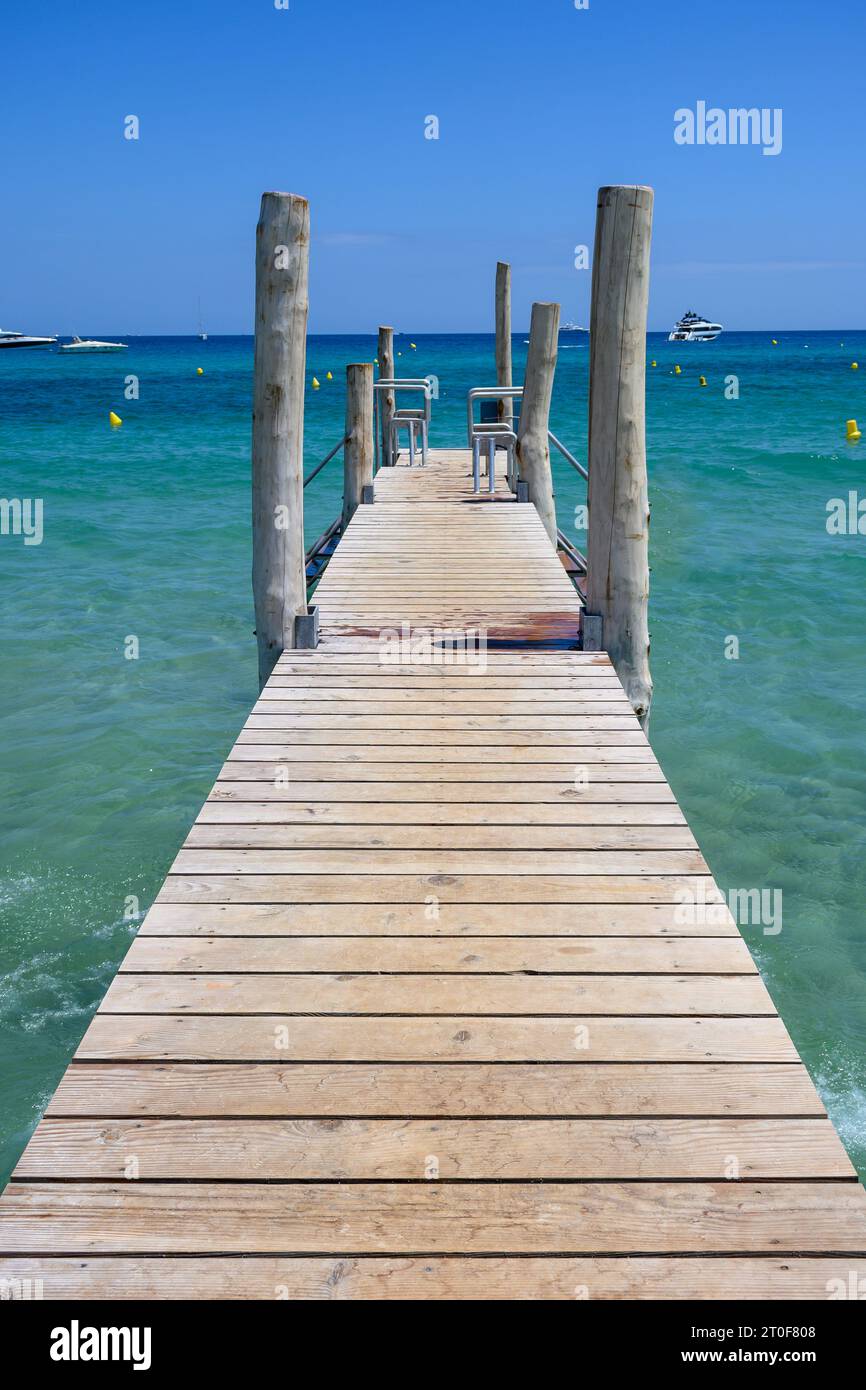 Wooden pier and crystal clear blue water of legendary Pampelonne beach ...