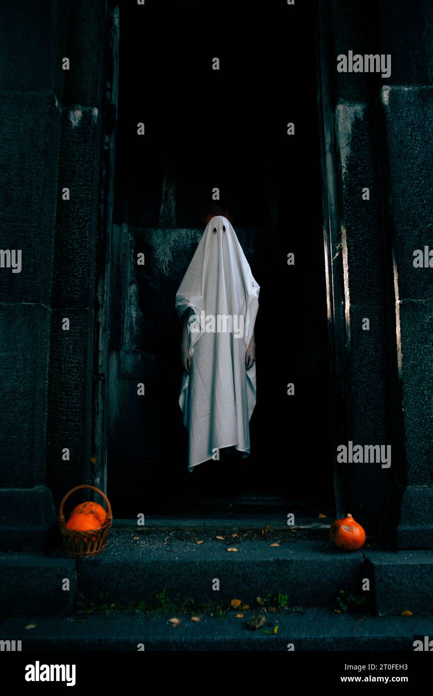 A ghost stands within a crypt adorned with pumpkins and autumn leaves ...