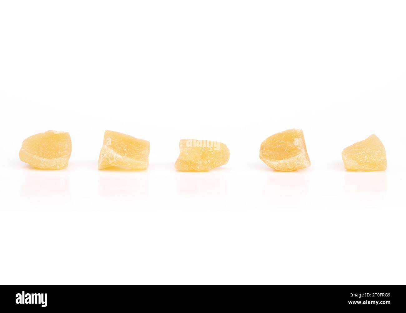 Isolated candied ginger pieces in a row. Yellow chunks of candied or ...