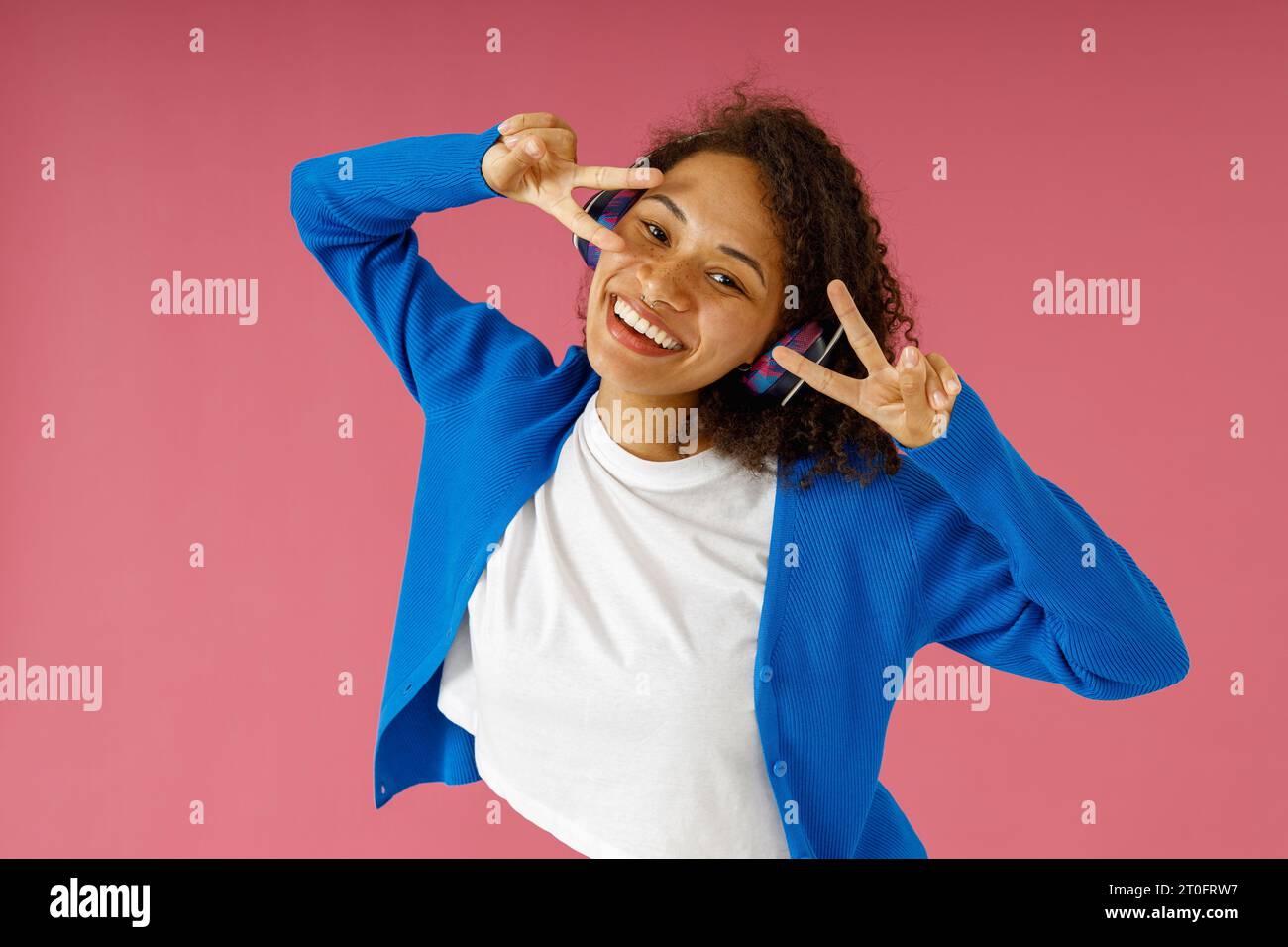 Stylish happy woman showing sign peace and looking at camera standing ...