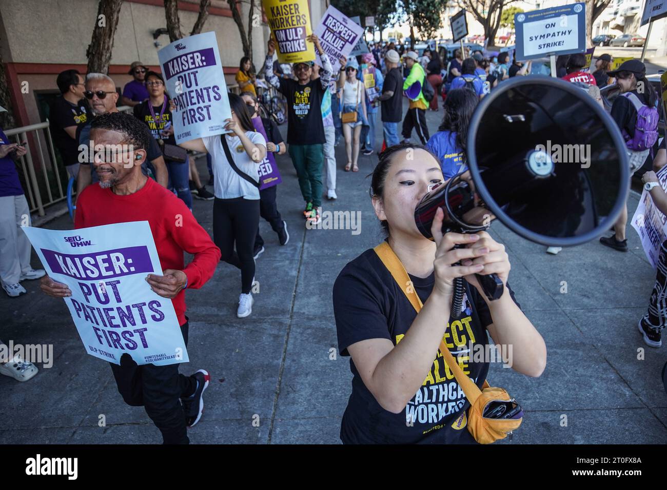 A Kaiser Permanente worker chants slogans on a megaphone during the ...
