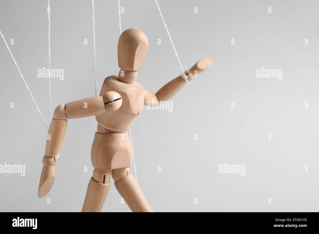 One wooden puppet with strings on light grey background. Space for text ...