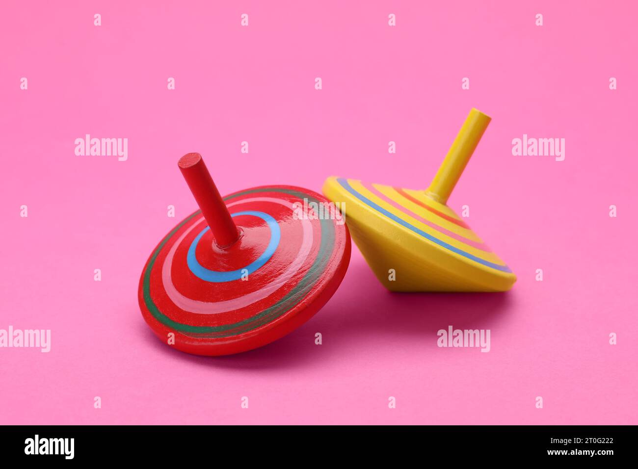 Two bright spinning tops on pink background. Toy whirligig Stock Photo ...