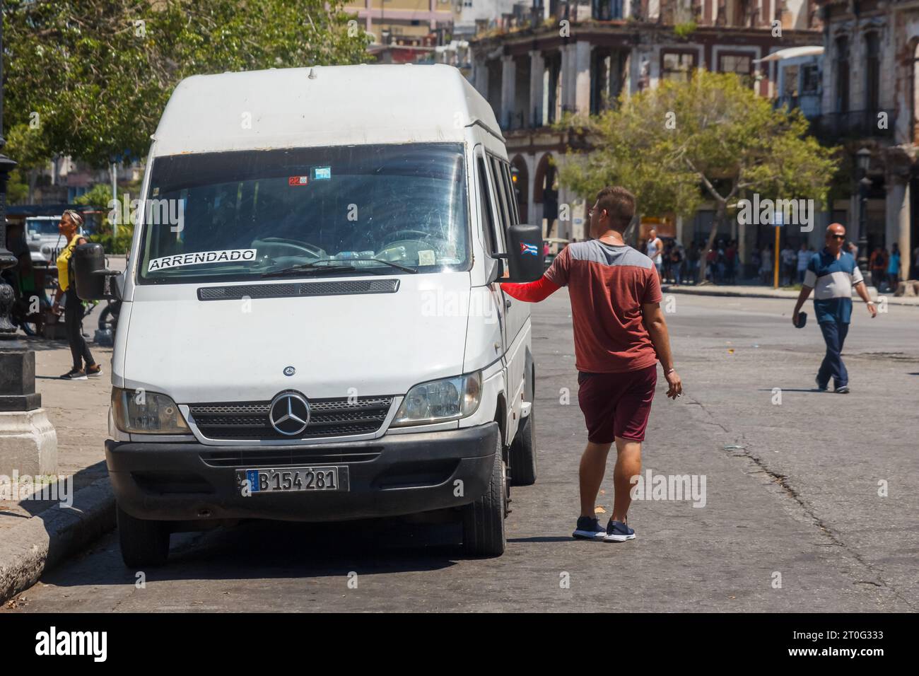 A Cuban man stands by a Mercedes Benz van vehicle in the downtown ...