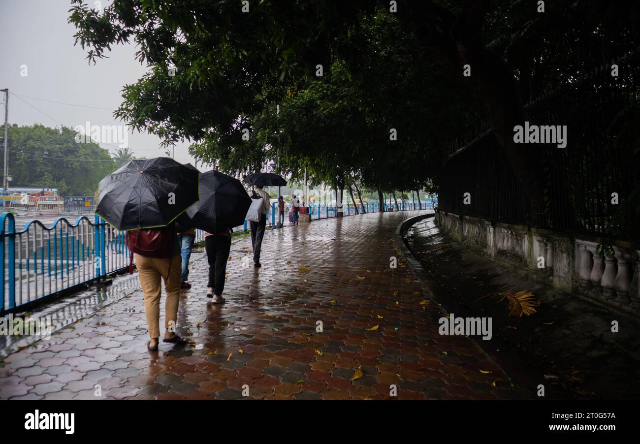 people walking with umbrella on a rain wet foot path and during monsoon ...