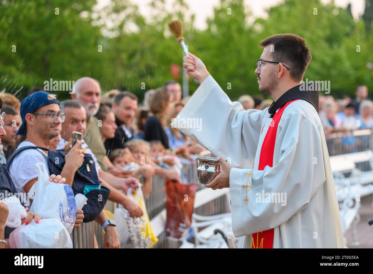 A priest blessing religious articles of the faithful after the evening ...