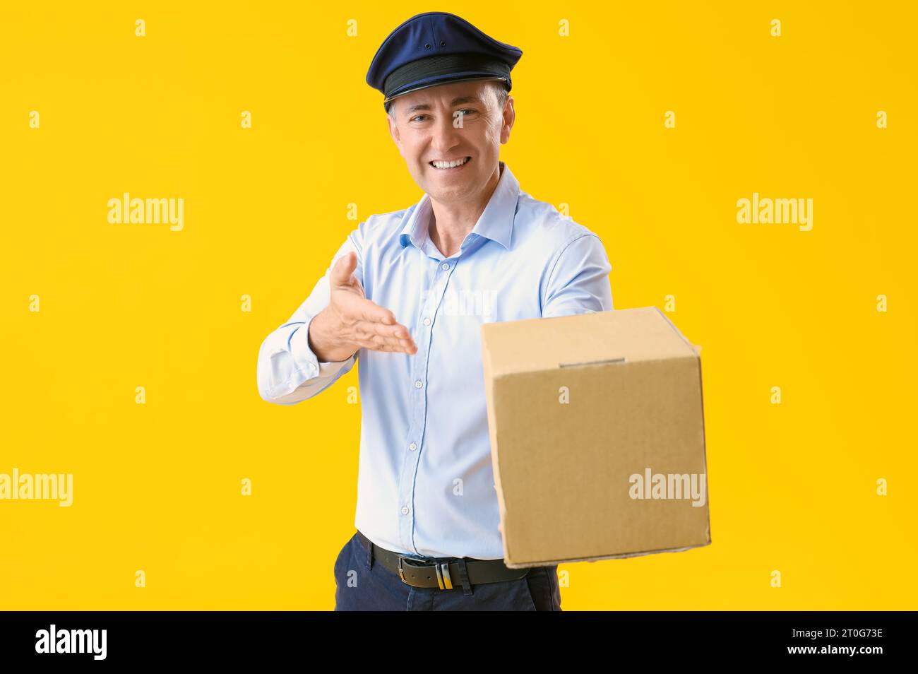 Mature postman with parcel on yellow background Stock Photo - Alamy