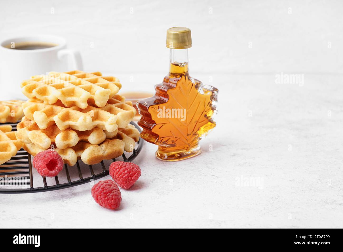 Grid of tasty waffles with raspberries and maple syrup on white ...