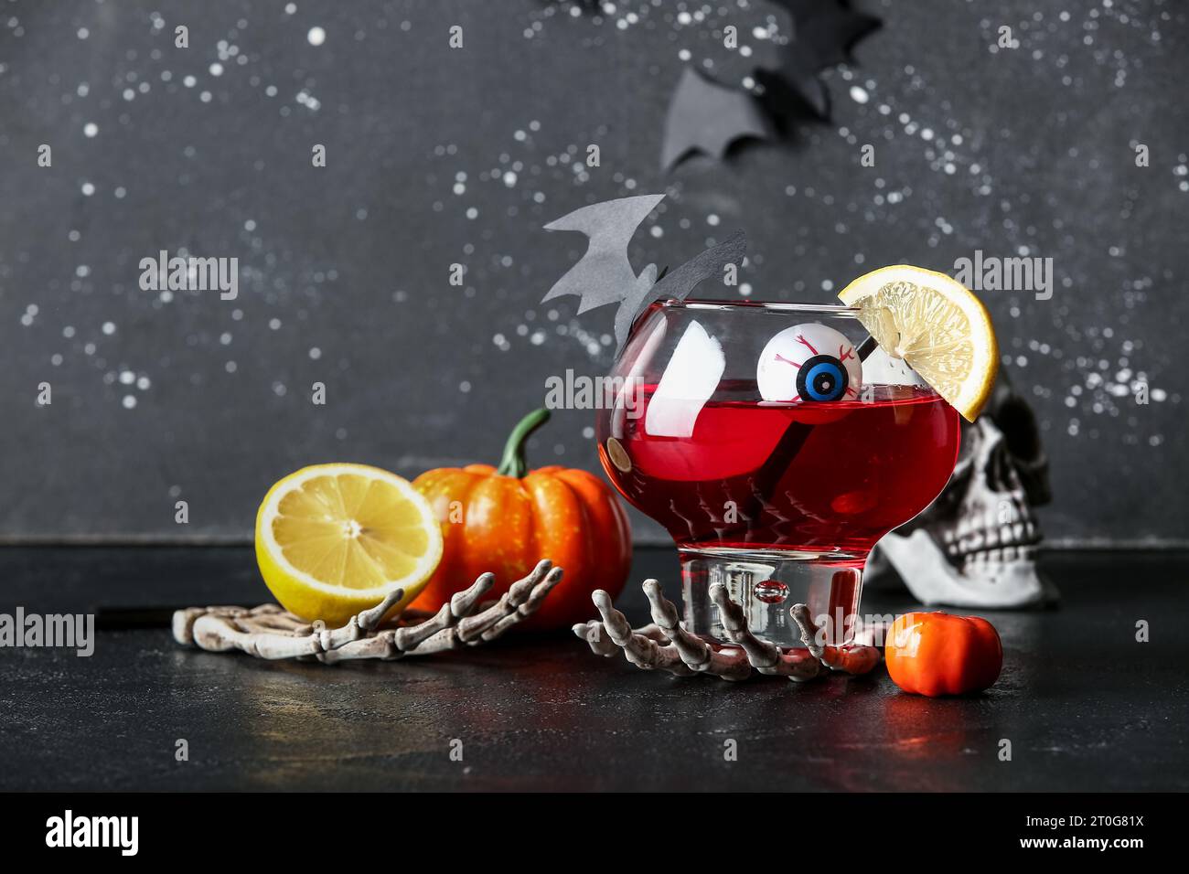 Glass of delicious cocktail, skeleton hands and lemon for Halloween ...