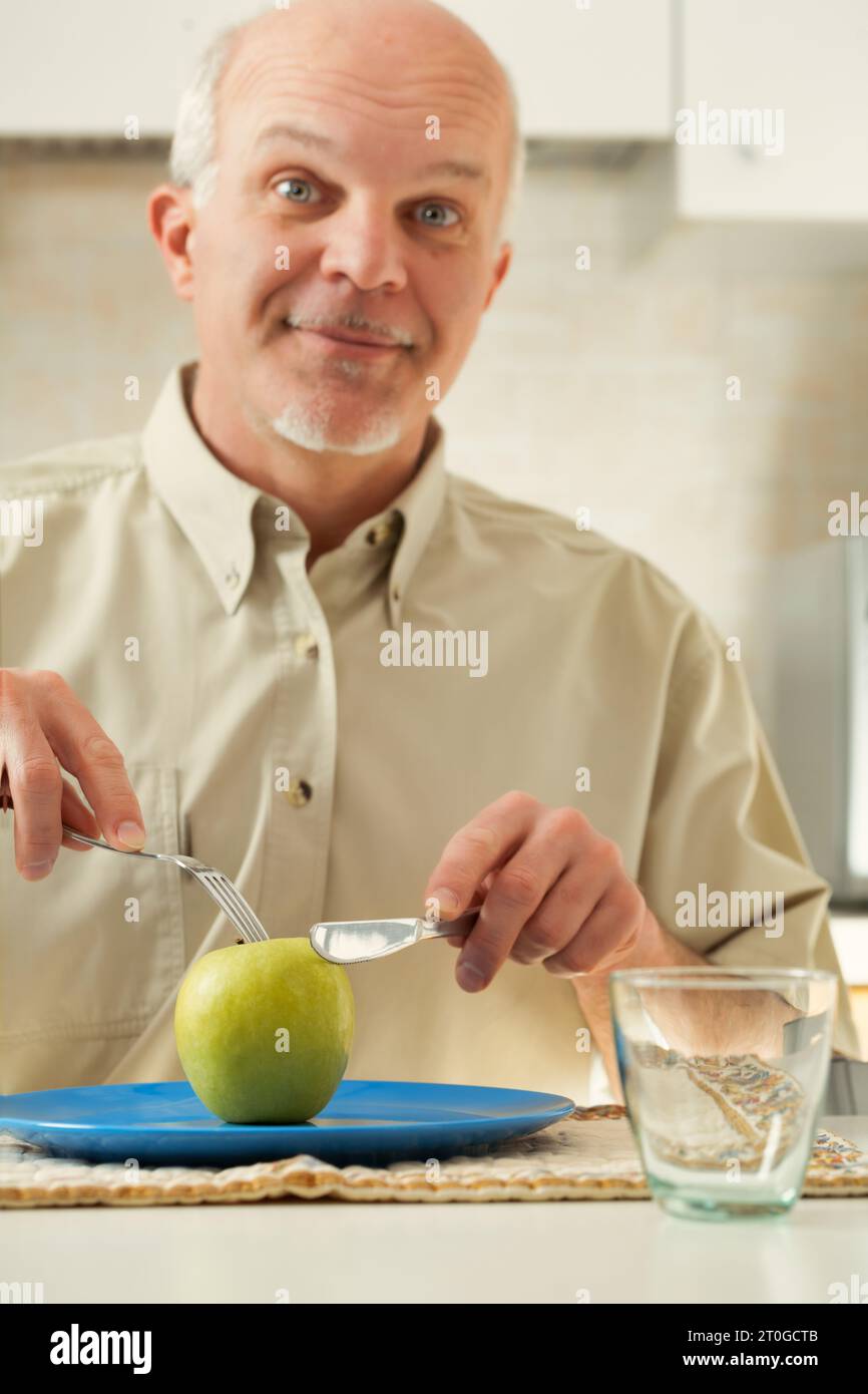 Elderly man, staring at a sole green apple, shows amusing reactions ...
