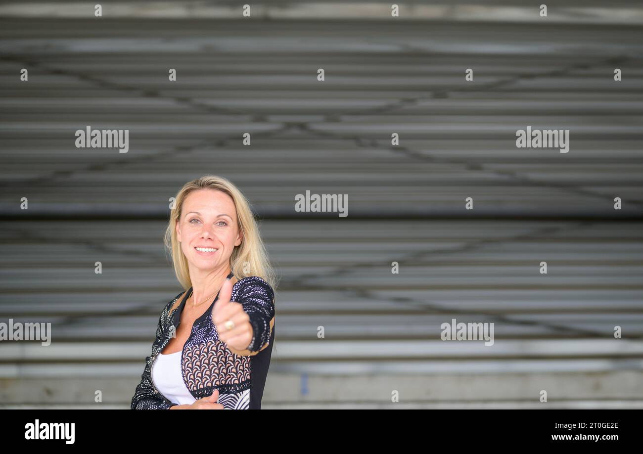 Upper body portrait of an attractive blonde woman giving a thumb up ...