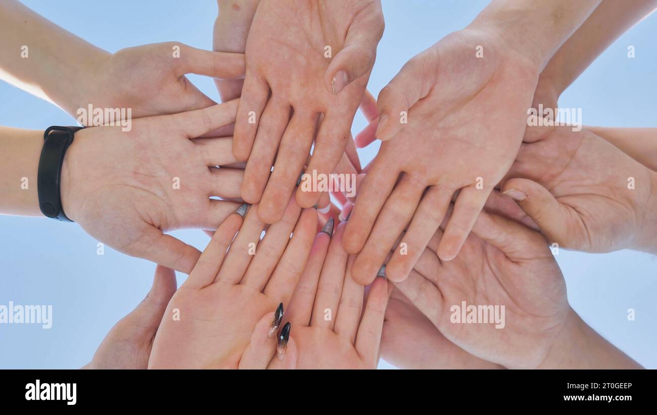 Friends putting their hands together in a sign of unity and teamwork ...