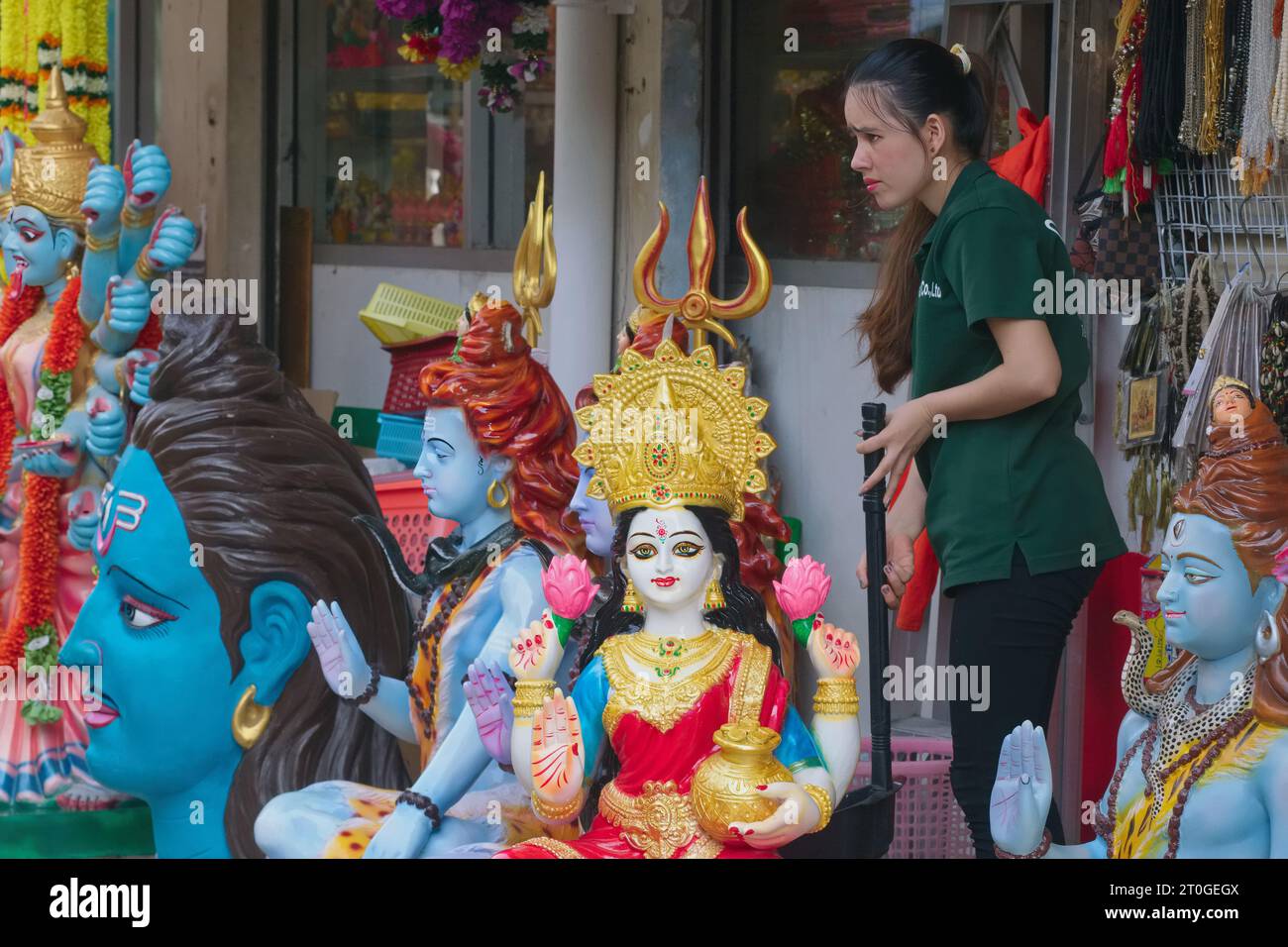 An ethnic Nepalese woman from Myanmar sweeping between colorful statues ...