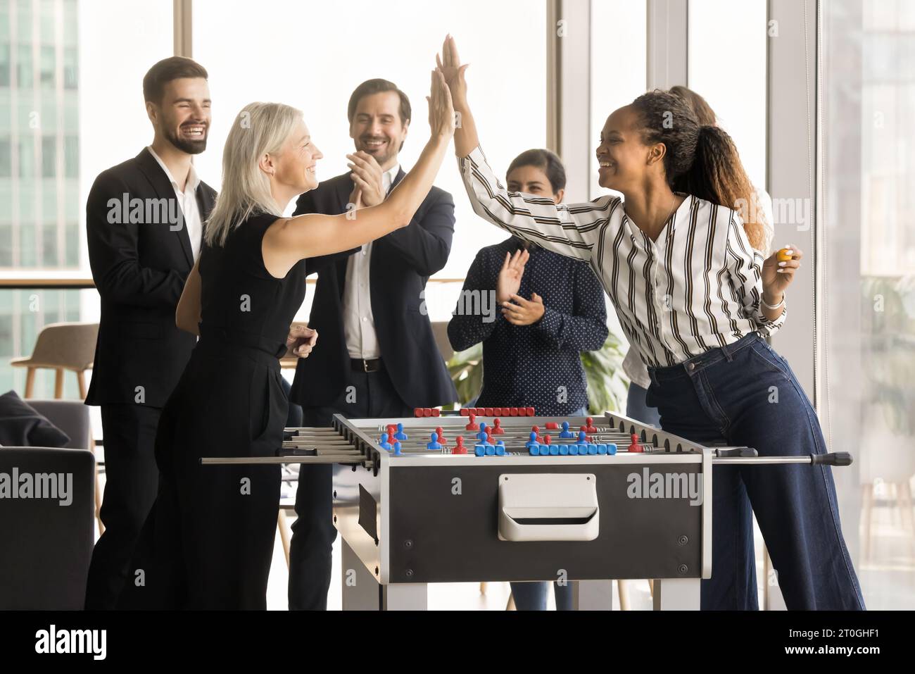 Cheerful positive colleagues women giving high five over game board ...