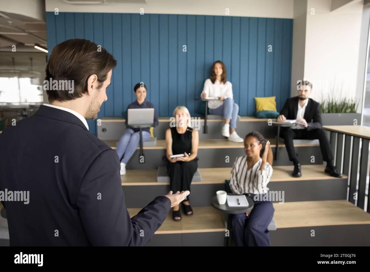 Business teacher, presenter man taking questions from small audience ...