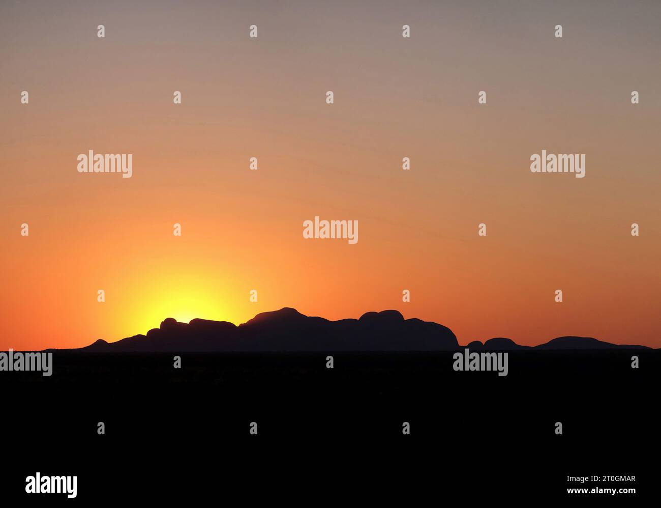 Kata Tjuta, (the Olgas) an orange sunset silhouette. A dark foreground ...