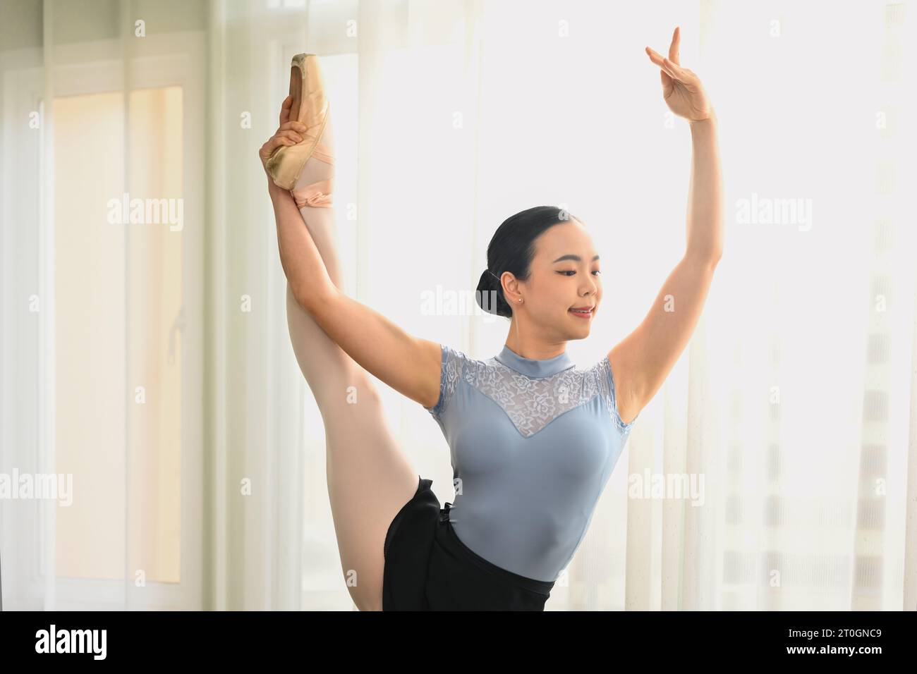 Elegant ballerina in pointe shoes raising leg high in Vertical Splits ...